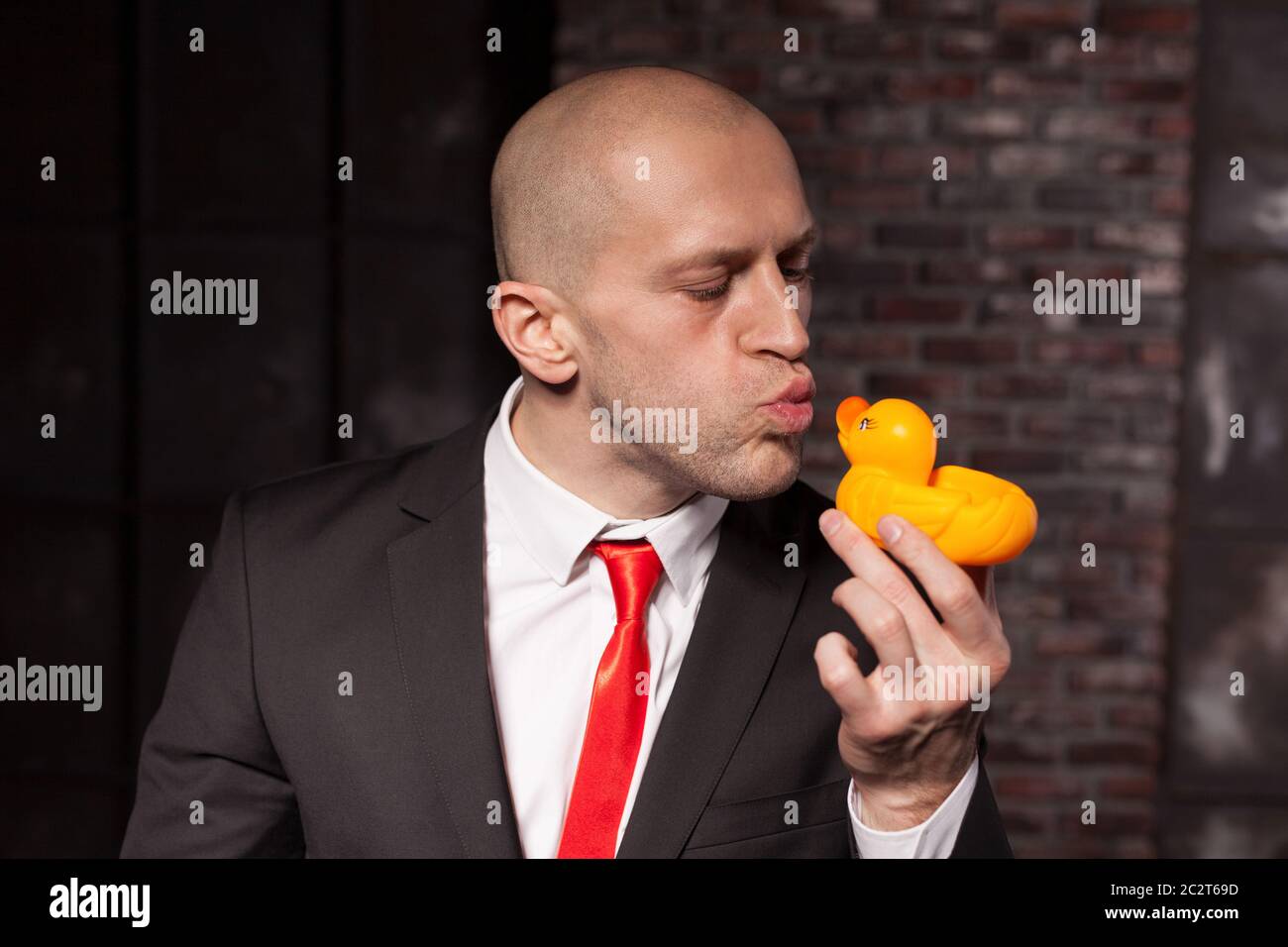 Special agent kissing little toy duck. Contract killer in suit and red ...