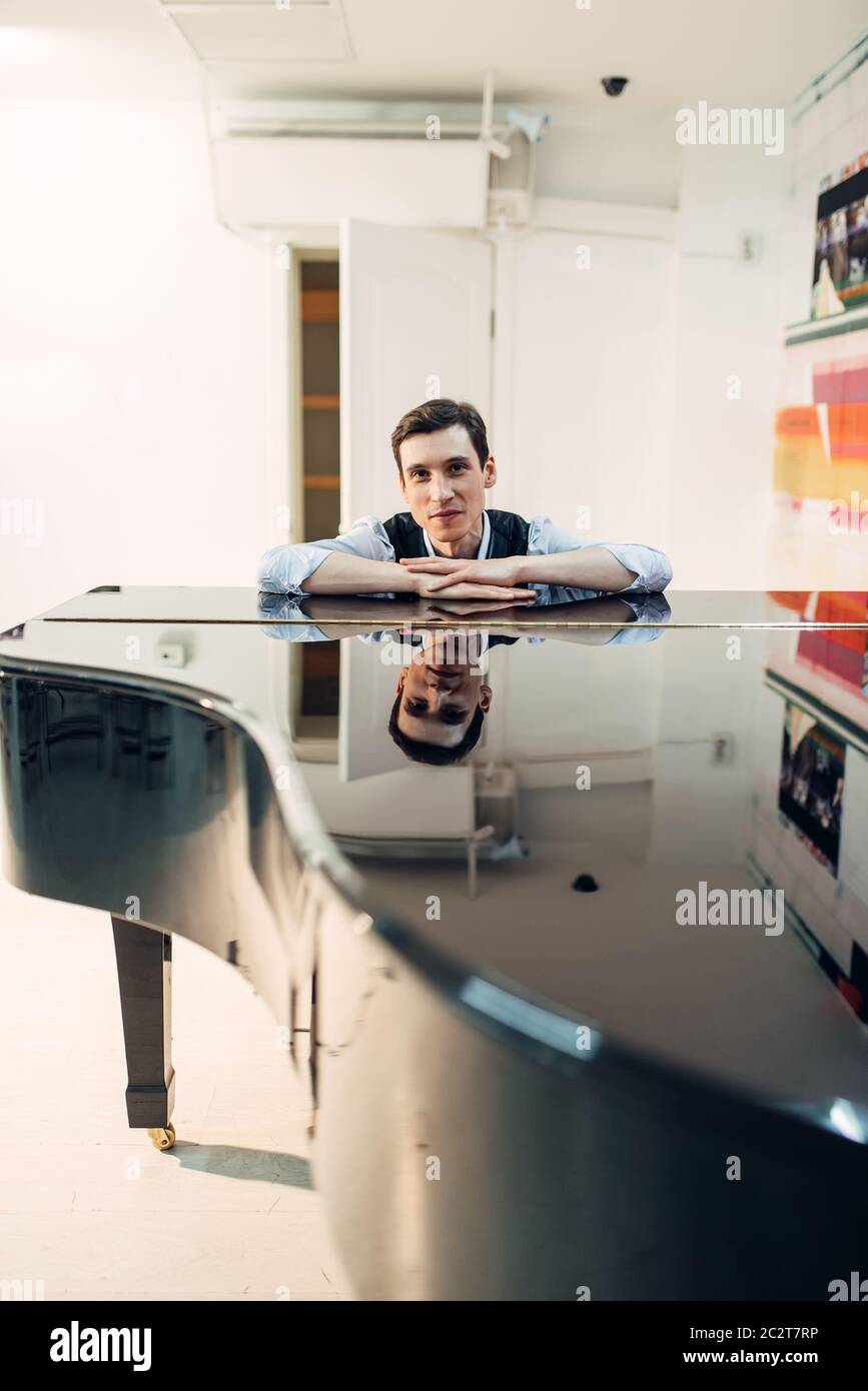 Male pianist at the classical black grand piano with perfectly polished ...