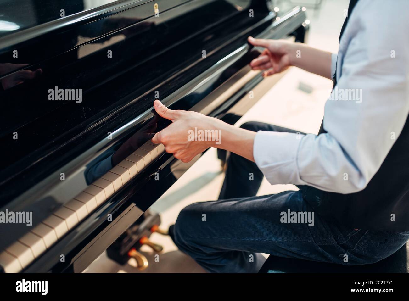 Male pianist opens the keyboard lid of the black grand piano. Musician ...