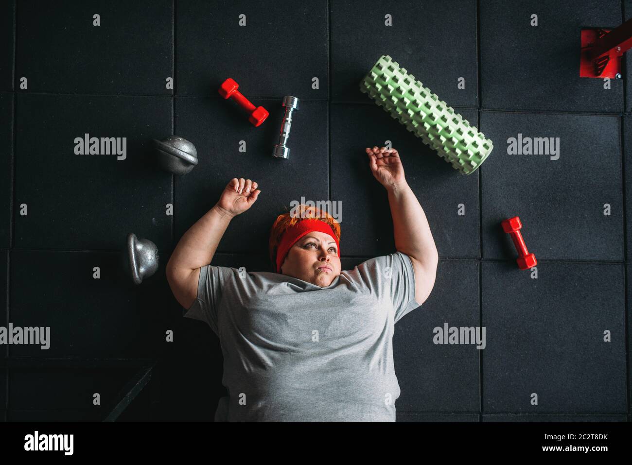 Tired fat woman lies on the floor in gym. Calories burning, obese ...