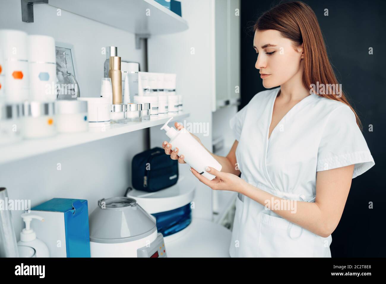 Young female beautician with bottle of cream in hands, cosmetology ...