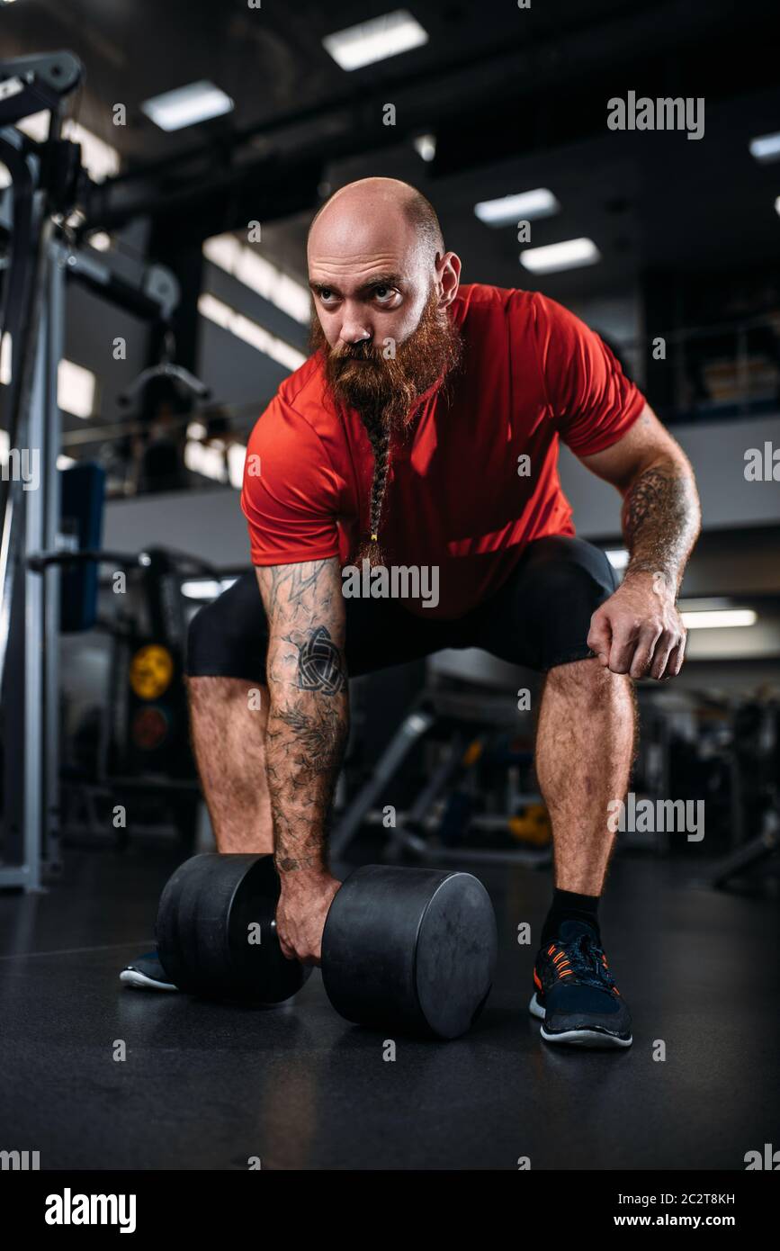 Athletic male lifter doing exercise with dumbbells in gym. Bearded ...