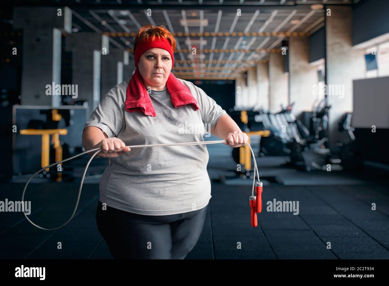 Fat sweaty woman, fitness exercise with rope in gym. Calories burning ...