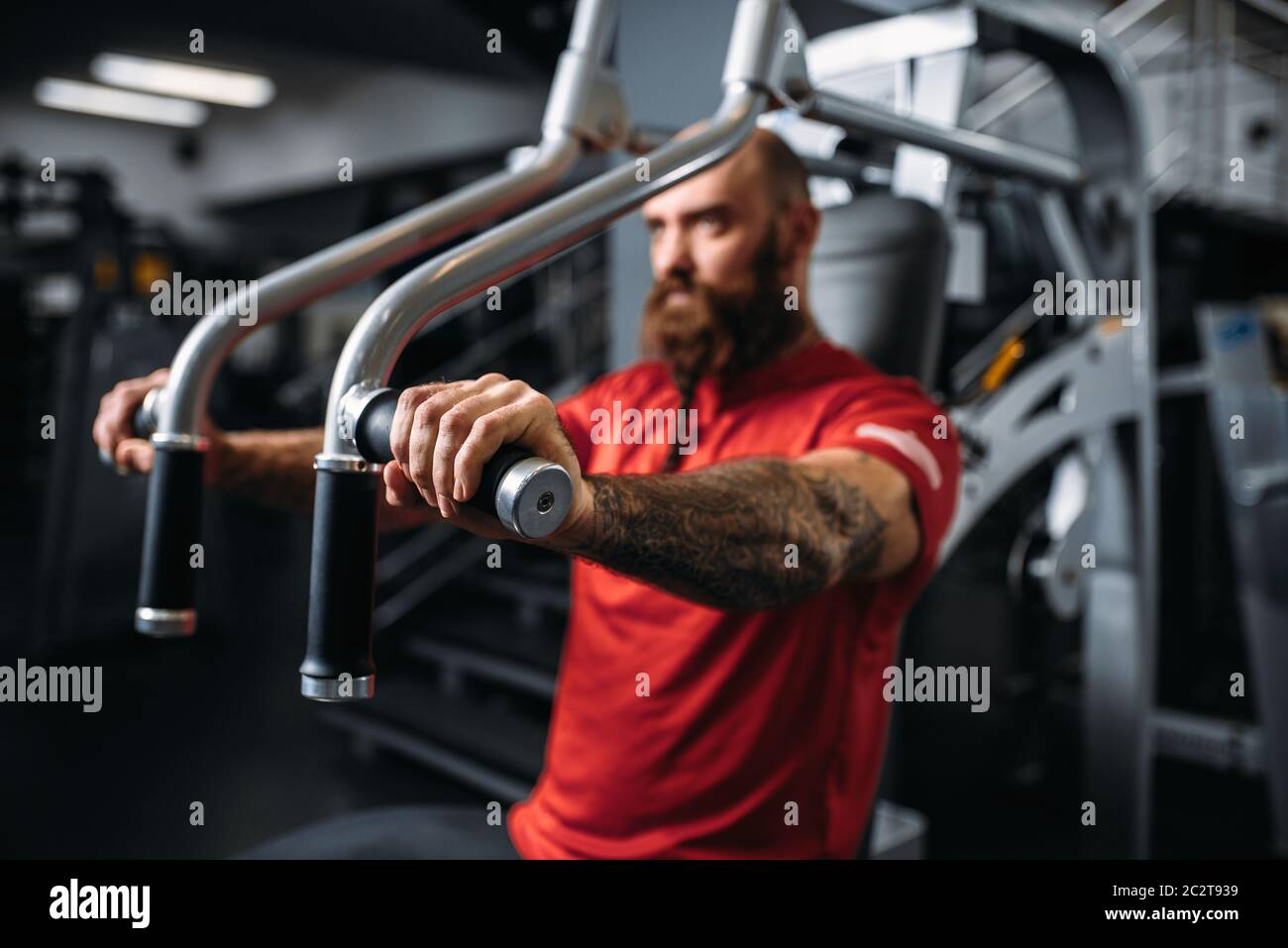 Muscular athlete on exercise machine in gym. Bearded man on workout in ...