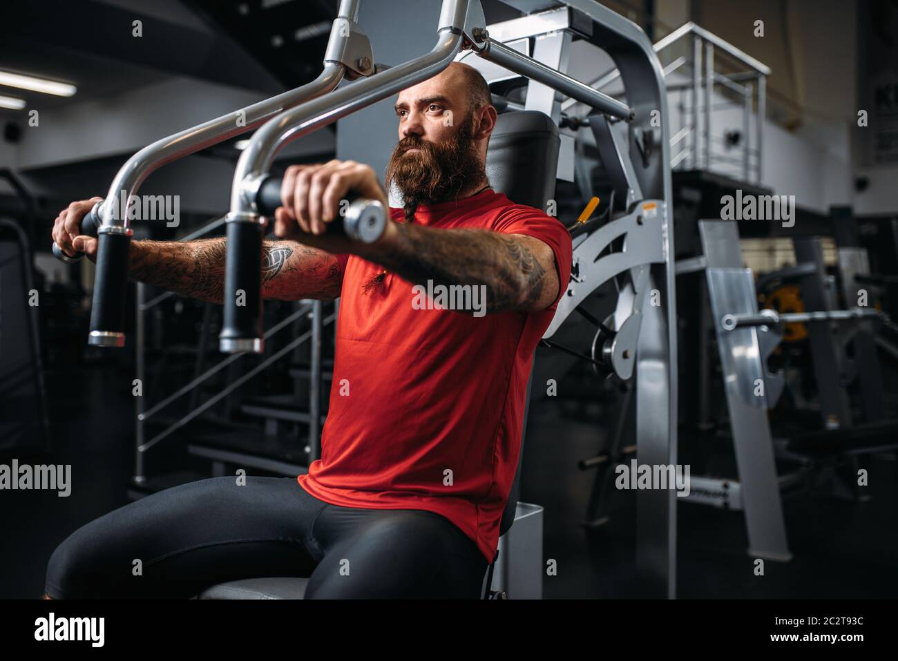 Muscular athlete on exercise machine in gym. Bearded man on workout in ...