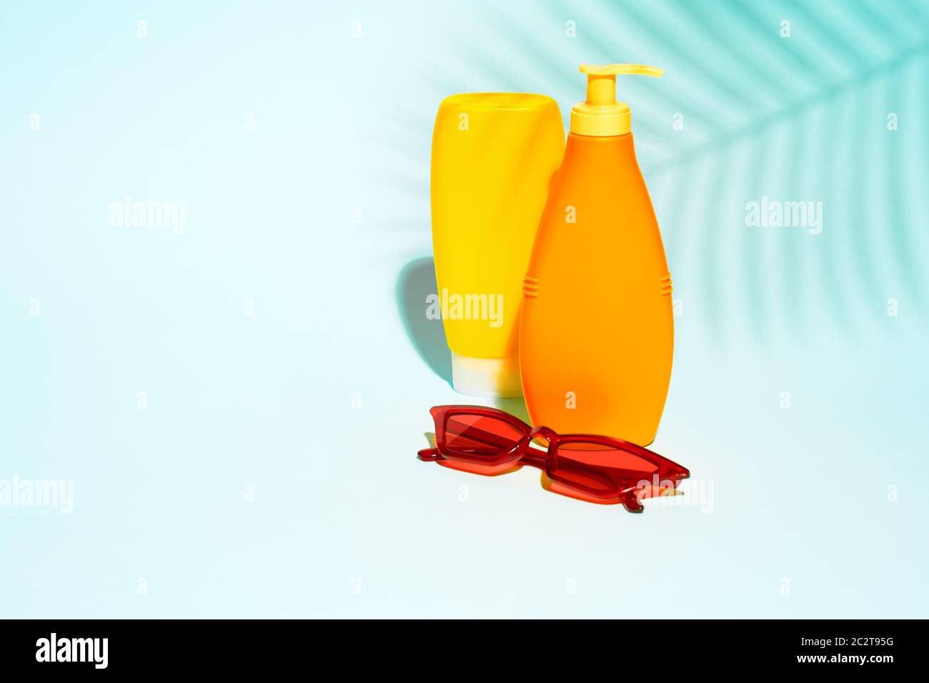 Two orange containers without label for lotion, red glasses on blue ...