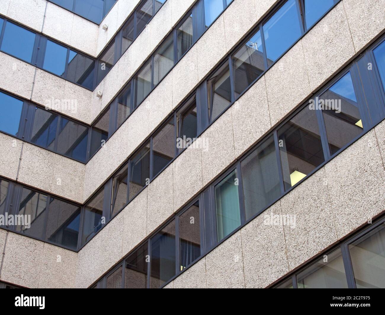 angled corner of a large concrete office building with other modern ...