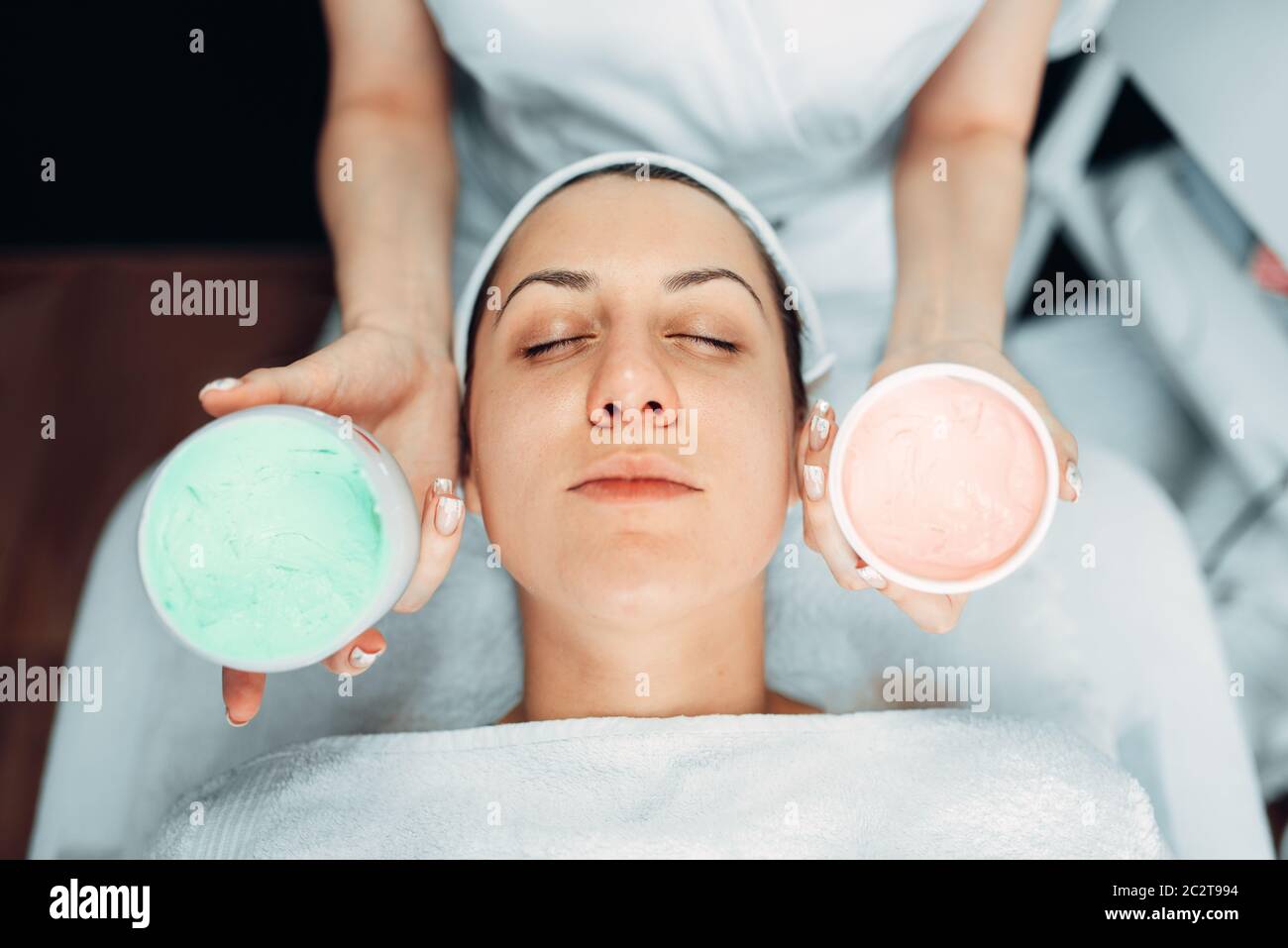 Beautician hands with cream against patient face rejuvenation cosmetic ...