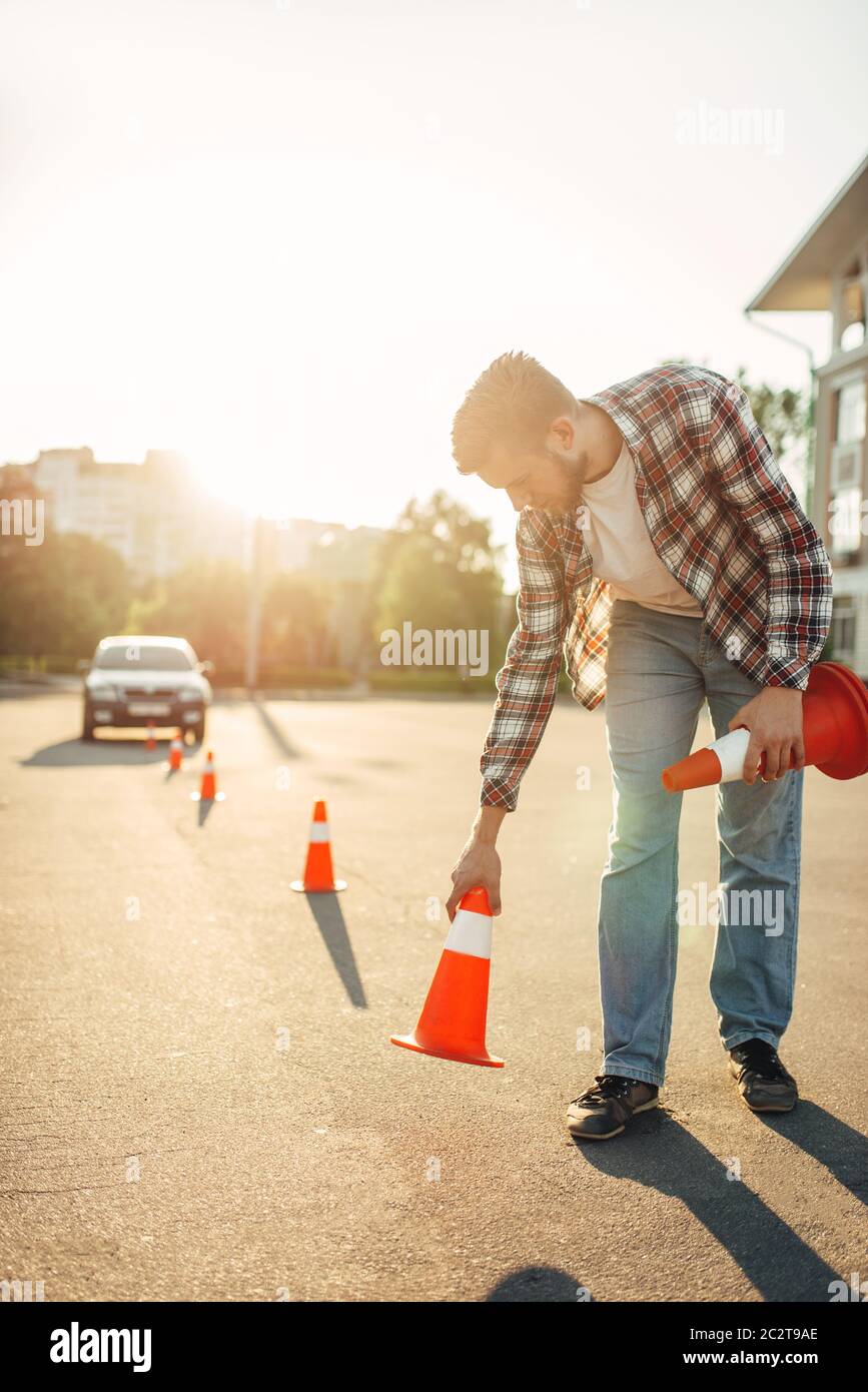 Instructor sets the cone for the examination, driving school concept ...