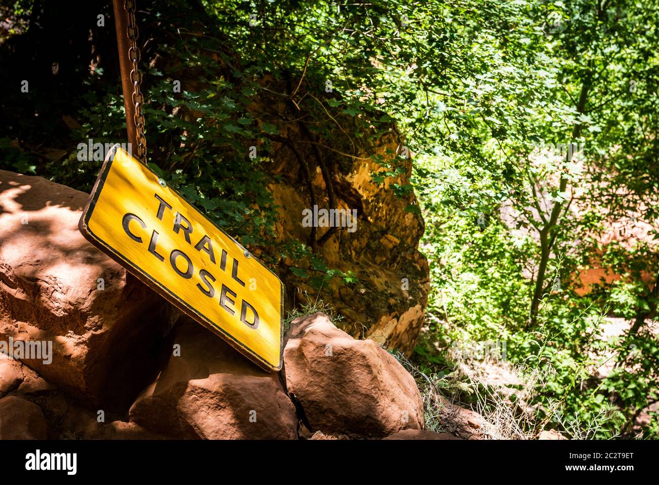 Stone mountain with green forest and trail closed sign Stock Photo - Alamy