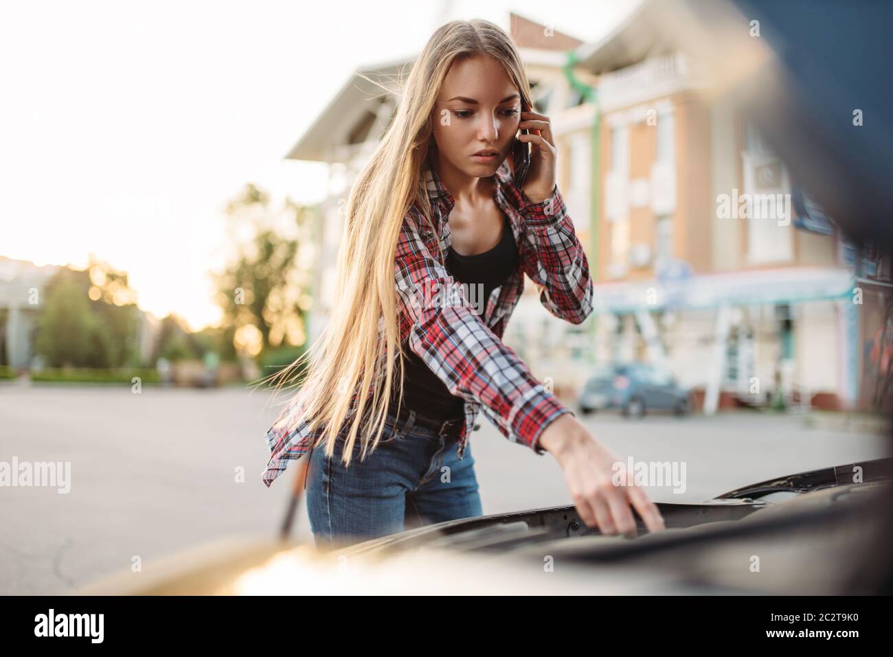 Car breakdown concept, sad woman against open bonnet on the roadside ...
