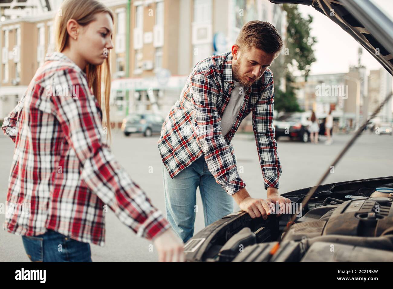 Car breakdown concept, sad couple against open hood. Female driver and ...