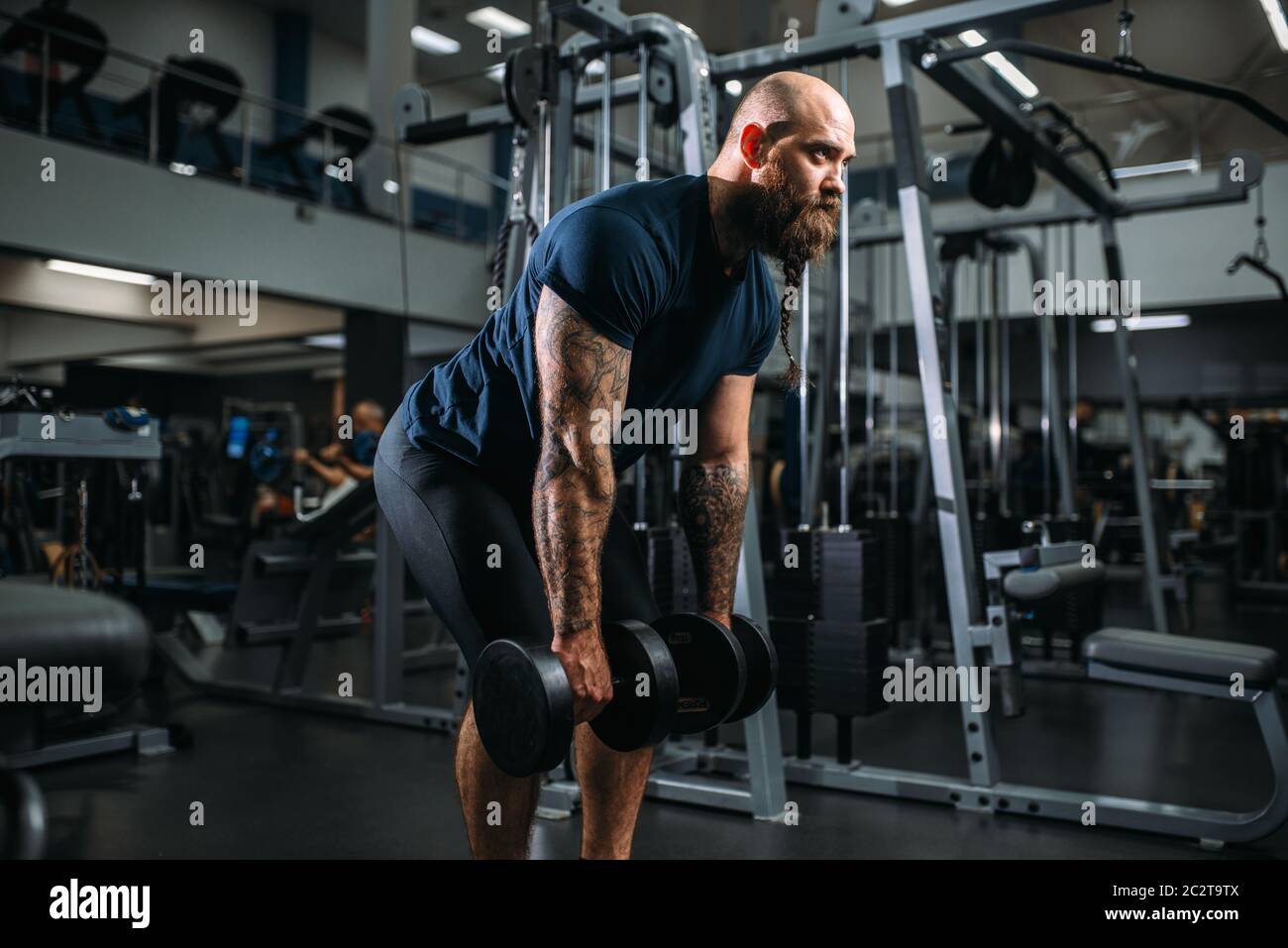 Strong athlete with dumbbells, training in gym. Bearded sportsman on ...