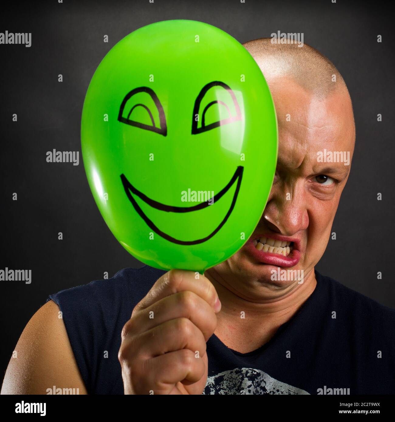 Angry man hiding behind green balloon with happy smiley Stock Photo - Alamy