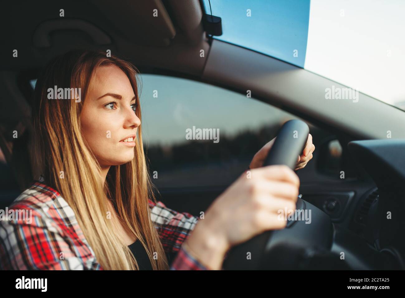 Young woman beginner driving a car, back view. Female person in vehicle ...