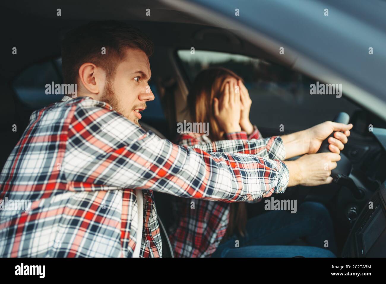 Male driving instructor helps the novice driver to avoid an accident ...