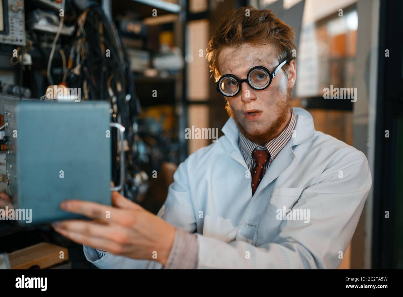 Crazy scientist in glasses holds electrical device in laboratory ...