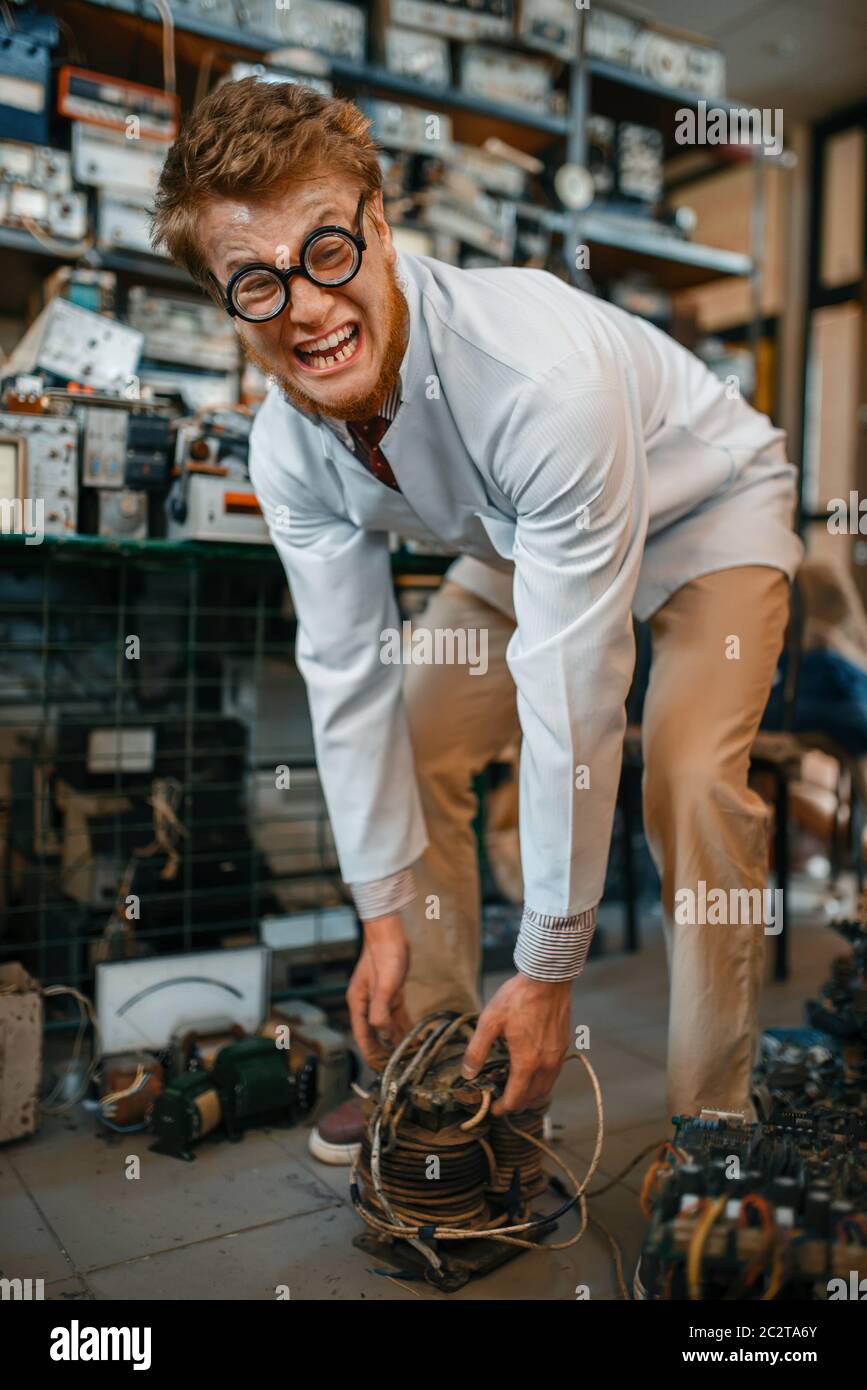 Crazy scientist lifts heavy electrical device in laboratory. Electrical ...