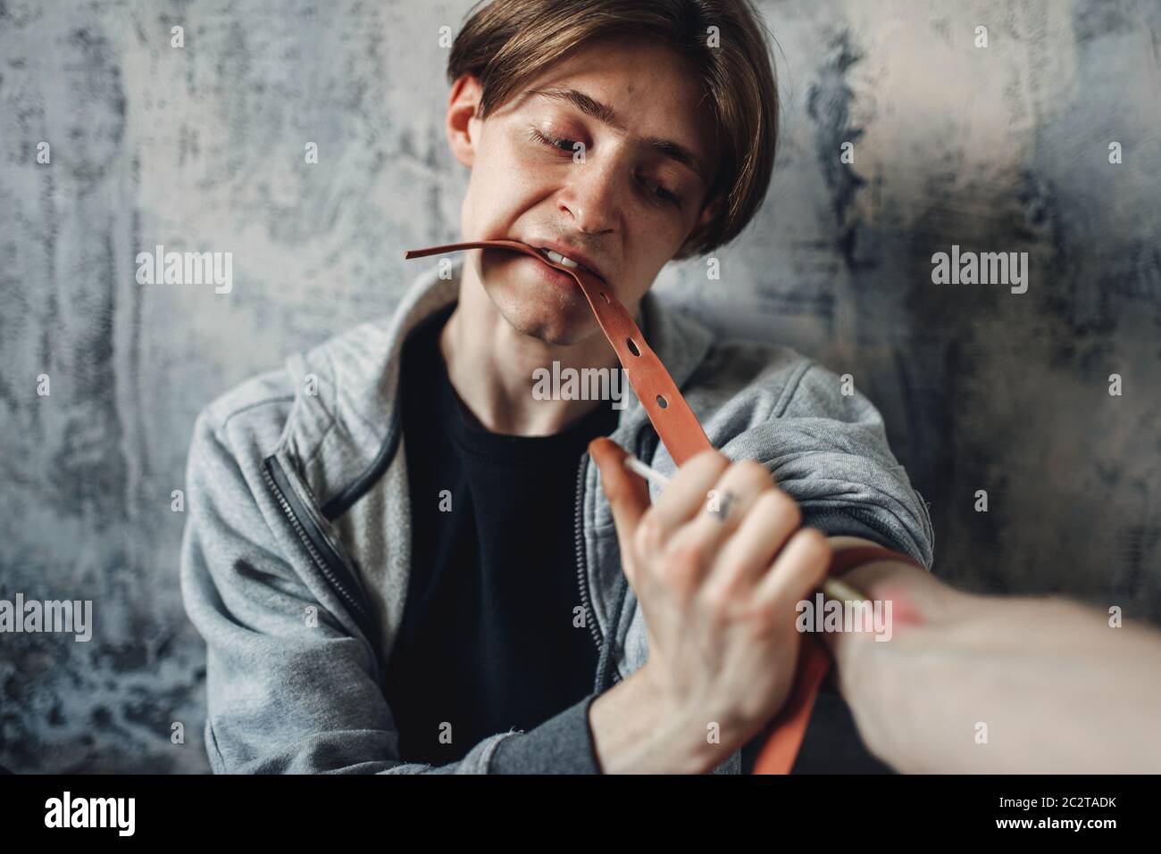 Male junkie with a syringe doing an injection dose in the arm. Narcotic ...