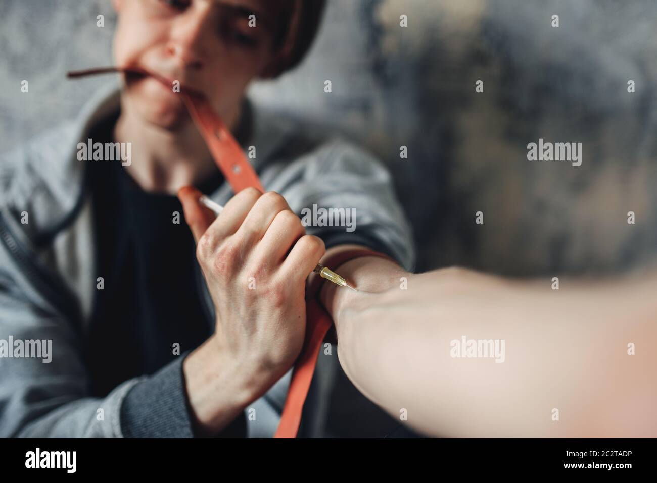 Male junkie with a syringe doing an injection dose in the arm. Narcotic ...