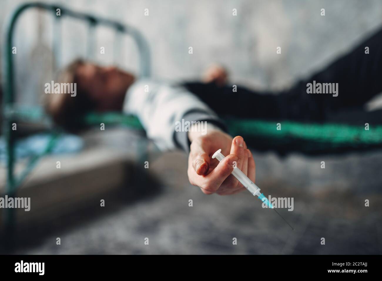 Male druggy with syringe in hand sleeping in bed after dose. Drug ...