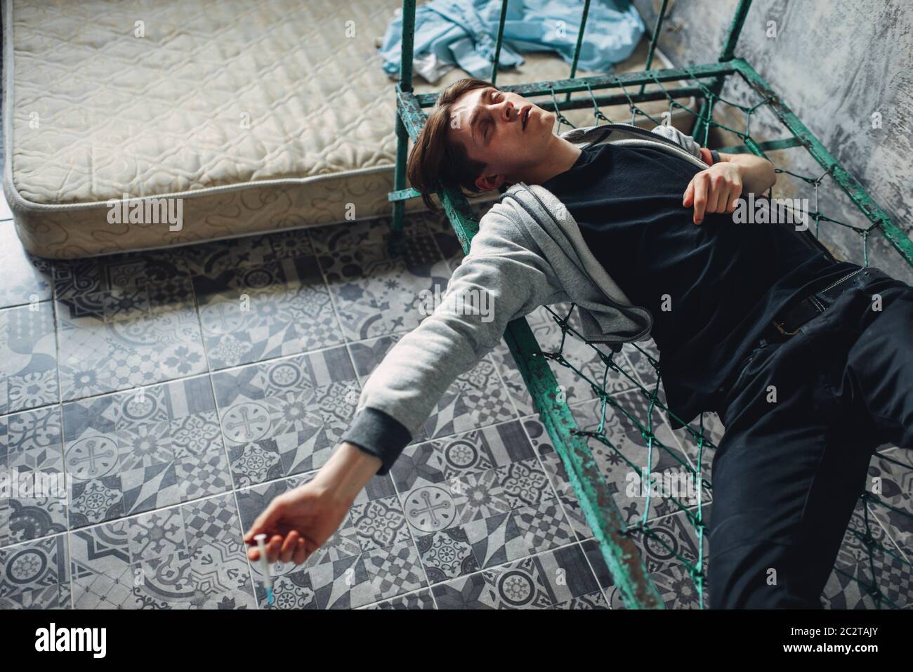 Male druggy with syringe in hand sleeping in bed after dose. Drug ...