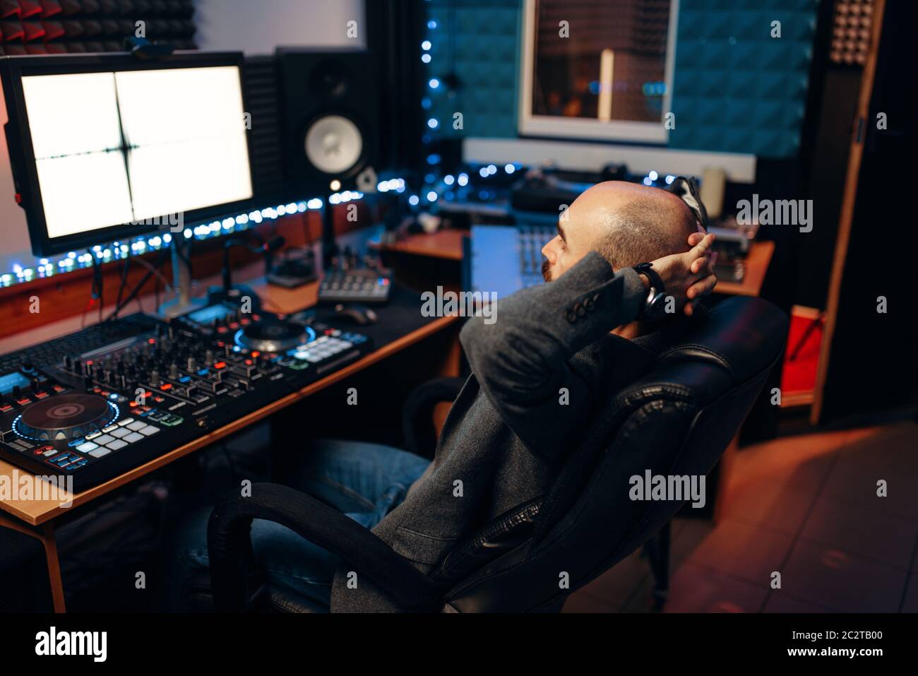 Male sound engineer at remote control panel, back view, recording ...