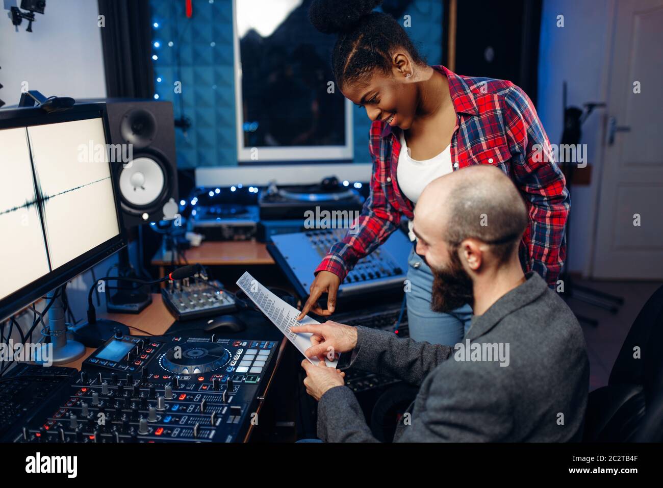 Sound operator and female singer at remote control panel in audio ...