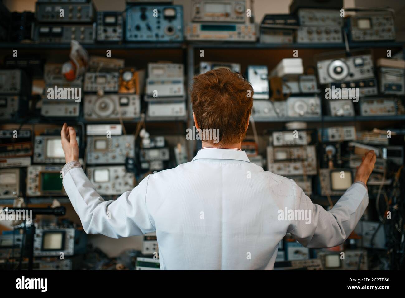 Strange scientist looking on shelf with electronic devices in ...
