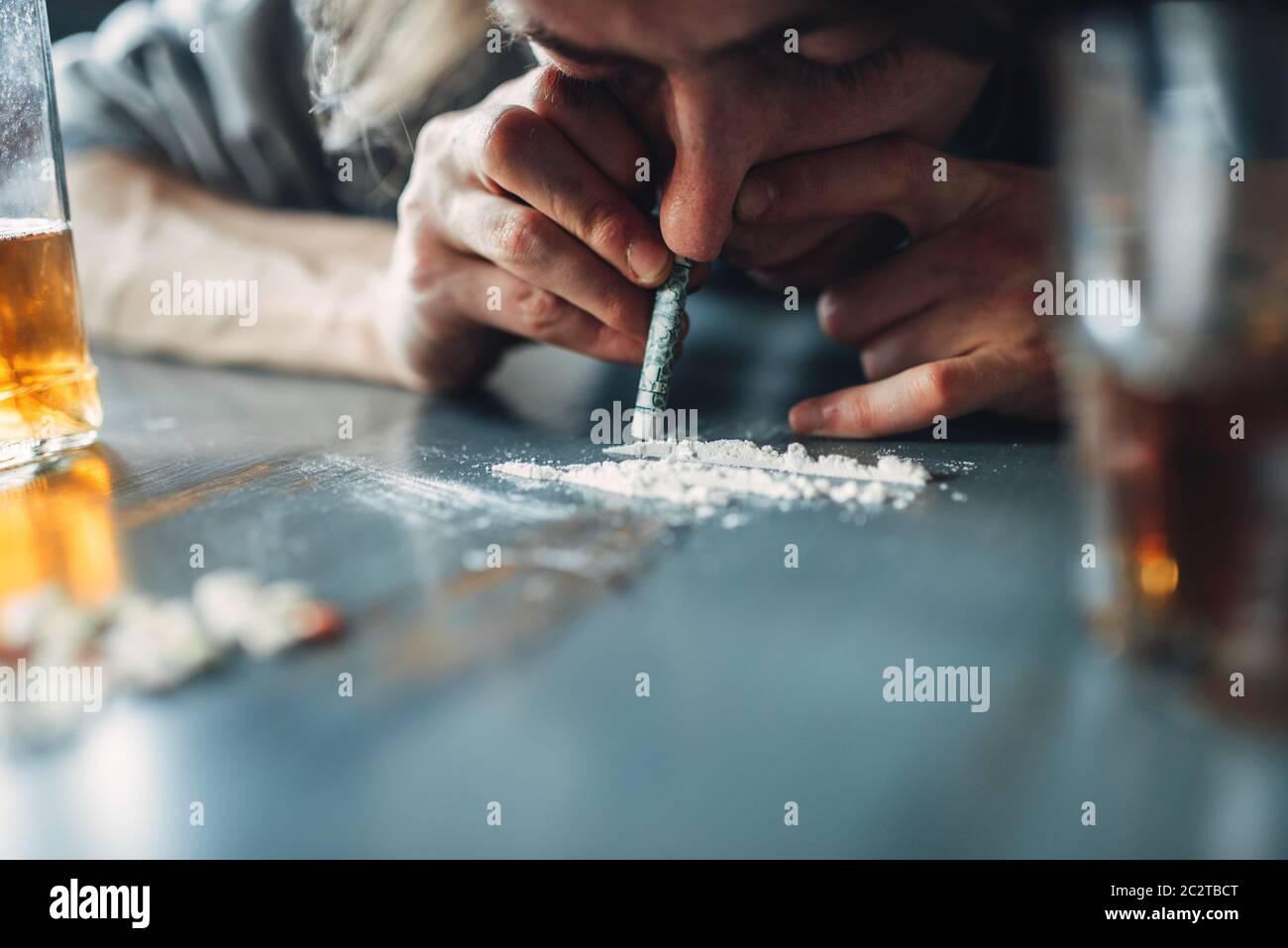 Male junkie sniffing a line of cocaine, grugs and bottle of alcohol on ...