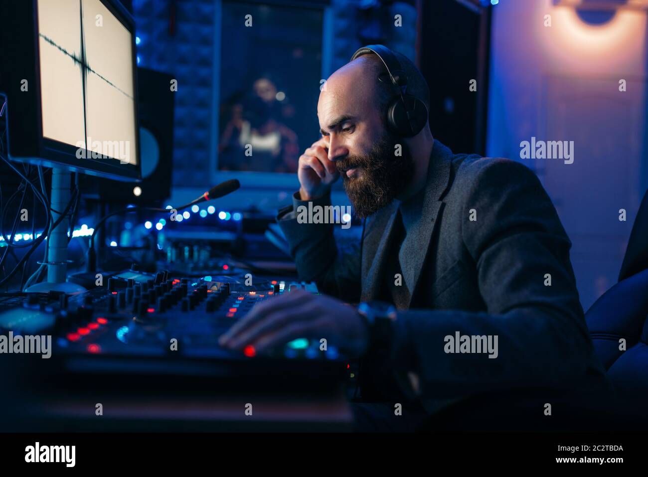 Sound engineer in headphones listens composition of female singer in ...