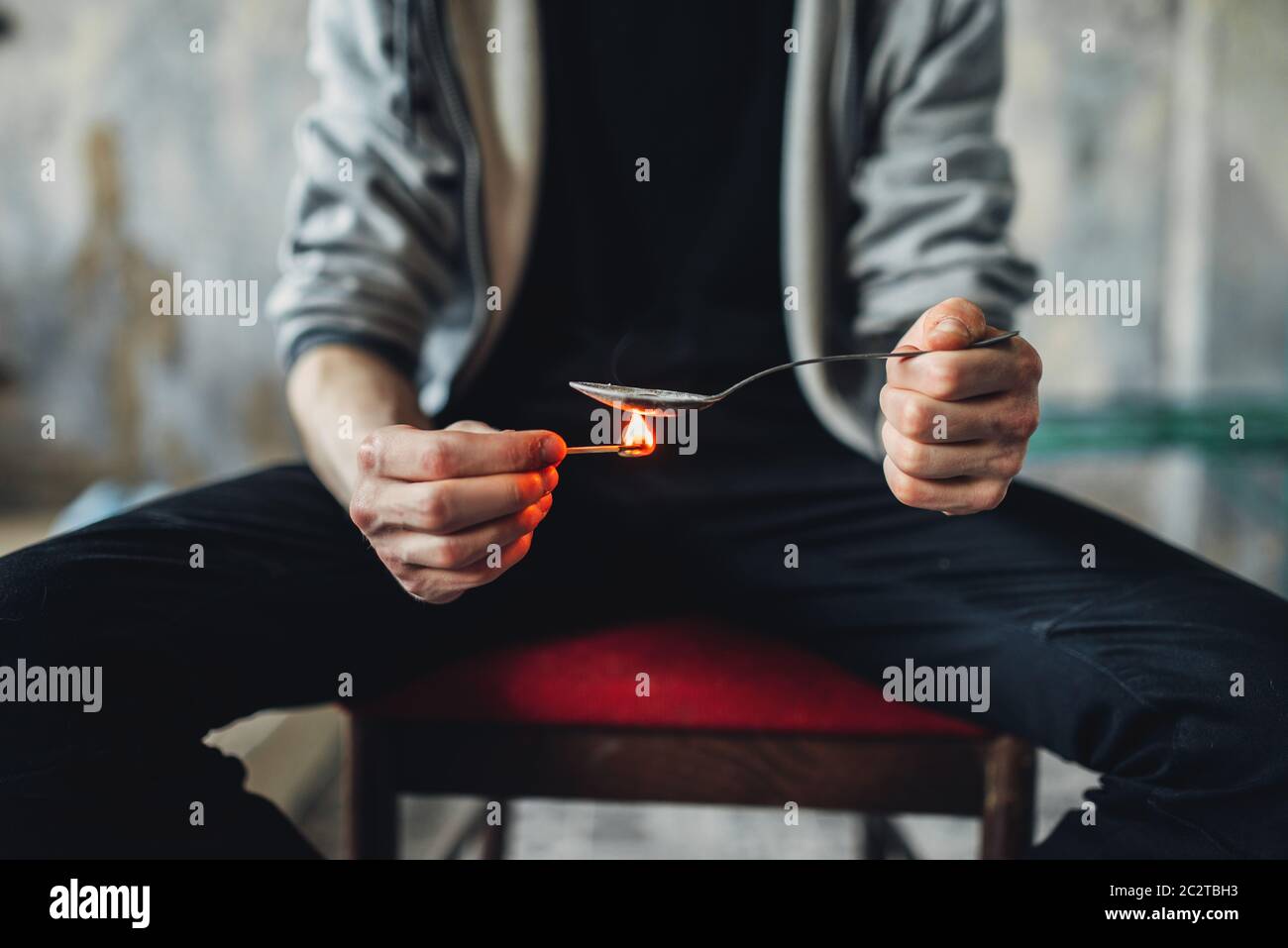 Junkie hands with a spoon and matches prepares a dose. Narcotic ...