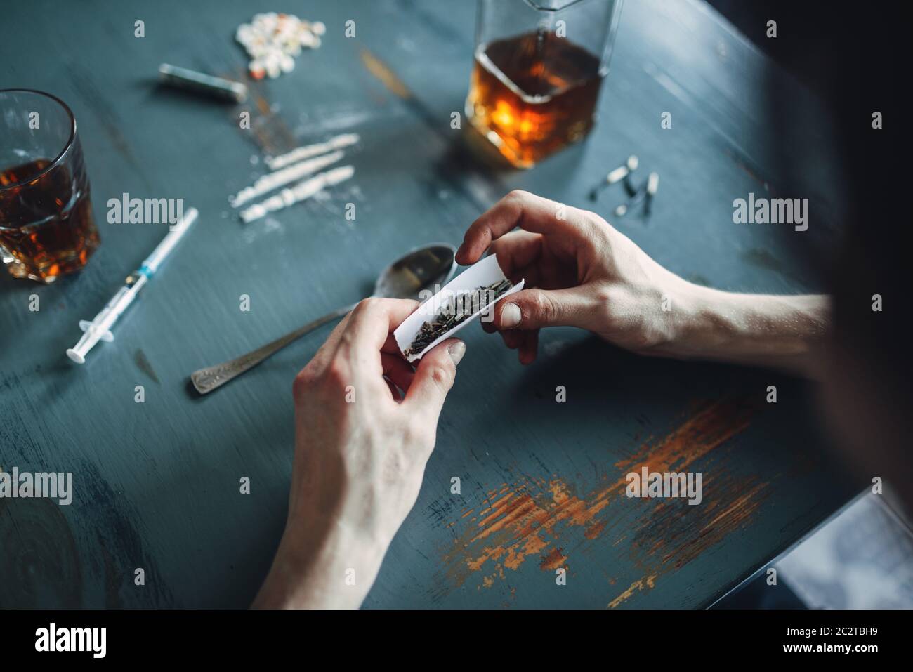 Drug addict hands prepares a dose, top view, bottle of alcohol and ...