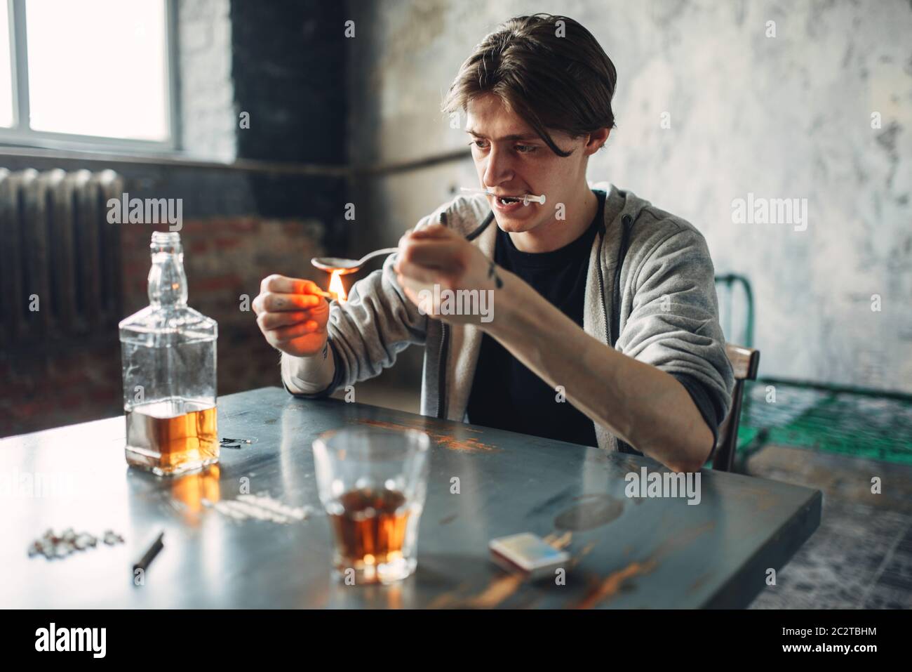 Drug addict with a spoon and matches prepares a dose. Narcotic ...