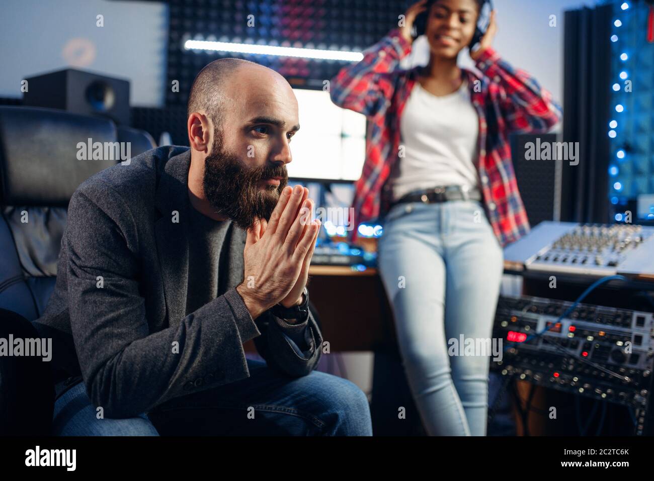 Sound producer and female singer in headphones listens composition in ...