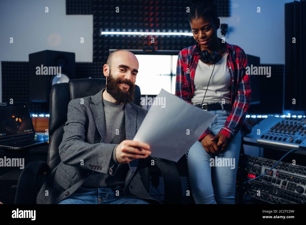 Male sound producer and female singer in headphones listens composition ...