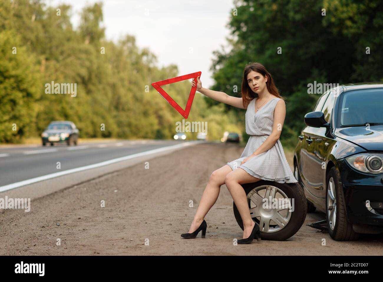 Car breakdown, young woman with emergency stop sign vote on the road ...