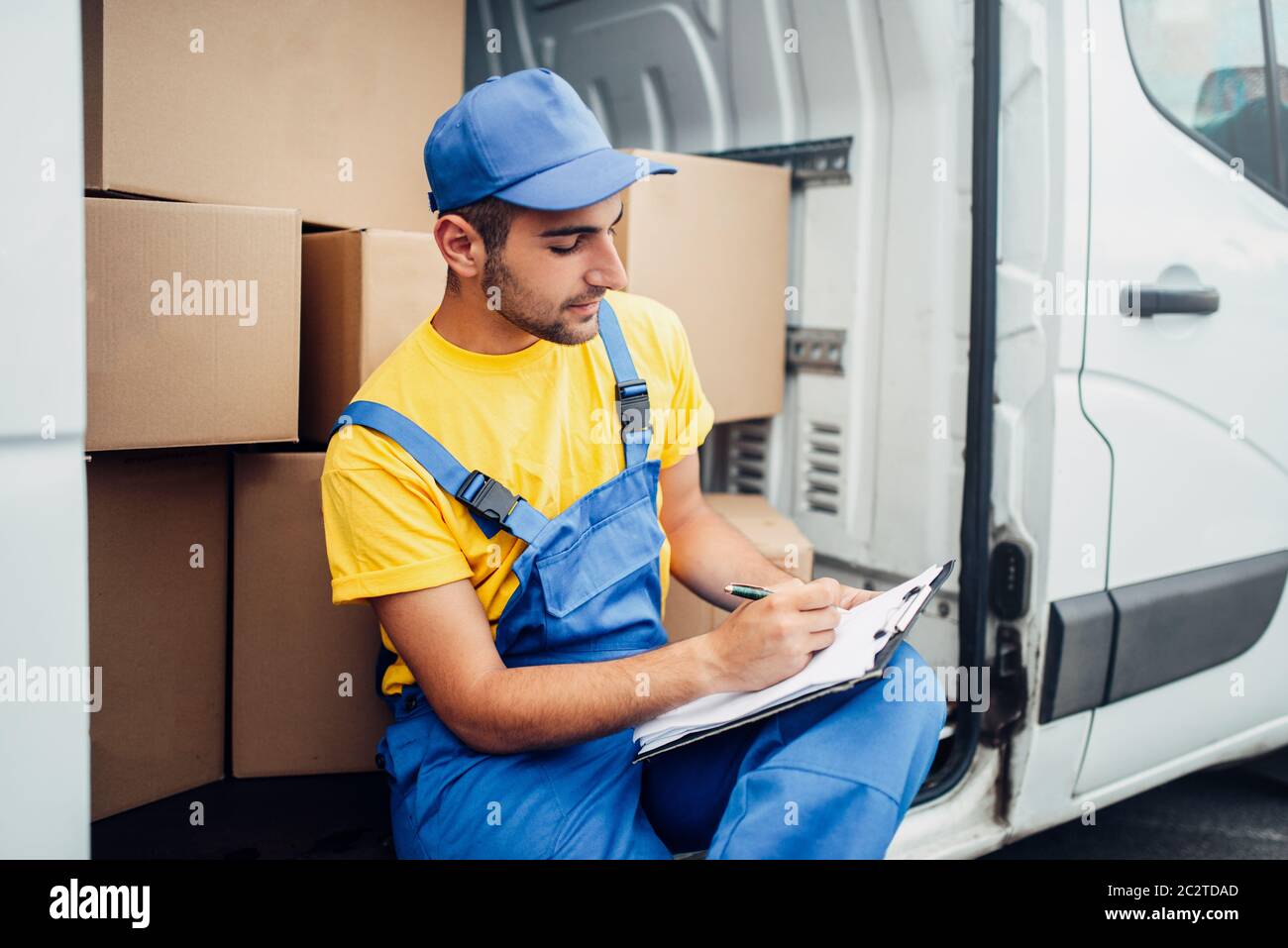 Cargo delivery service, male courier in uniform and truck with ...
