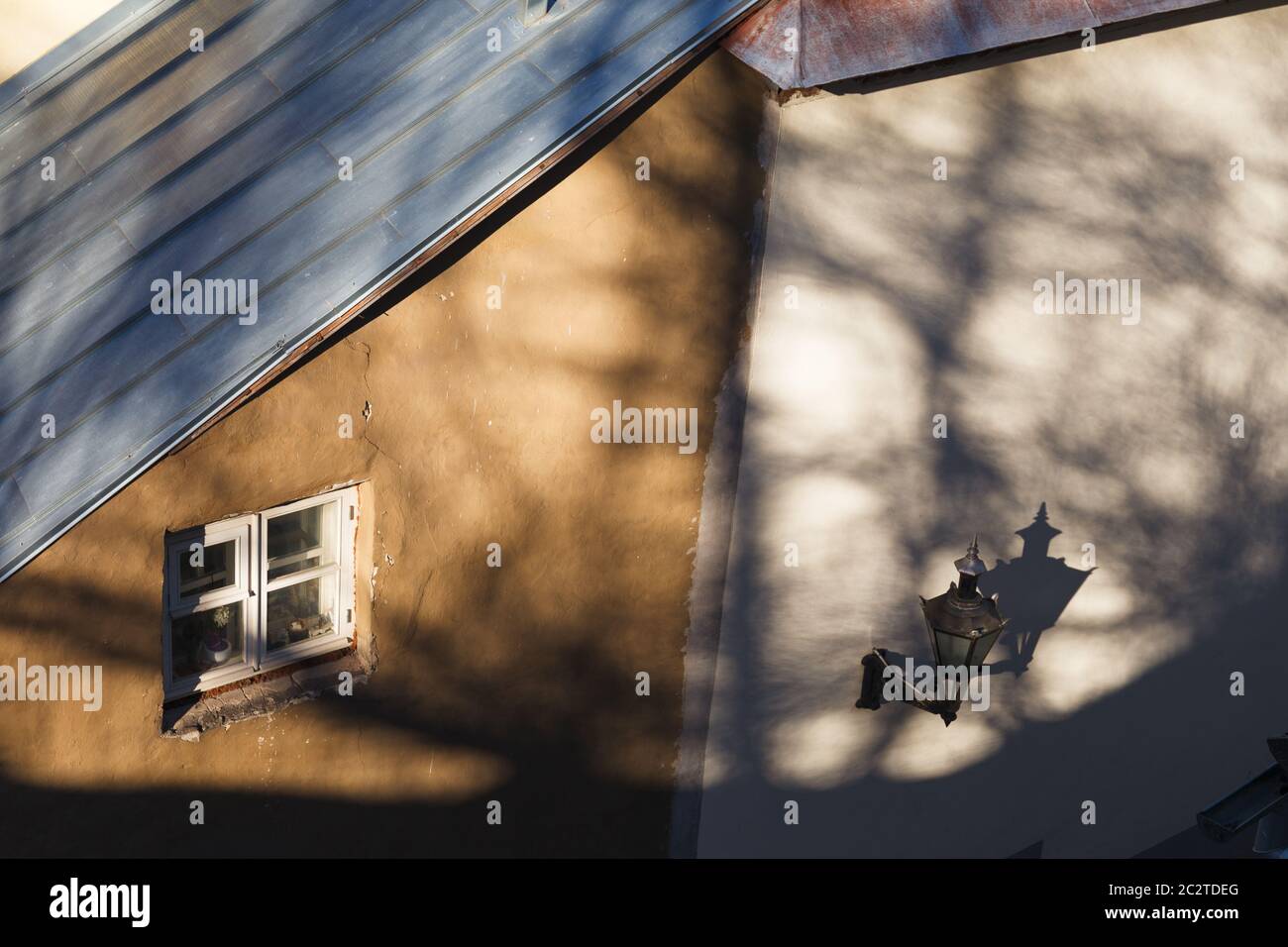 Old house wall with windows and lantern, covered by shadows. Old town ...