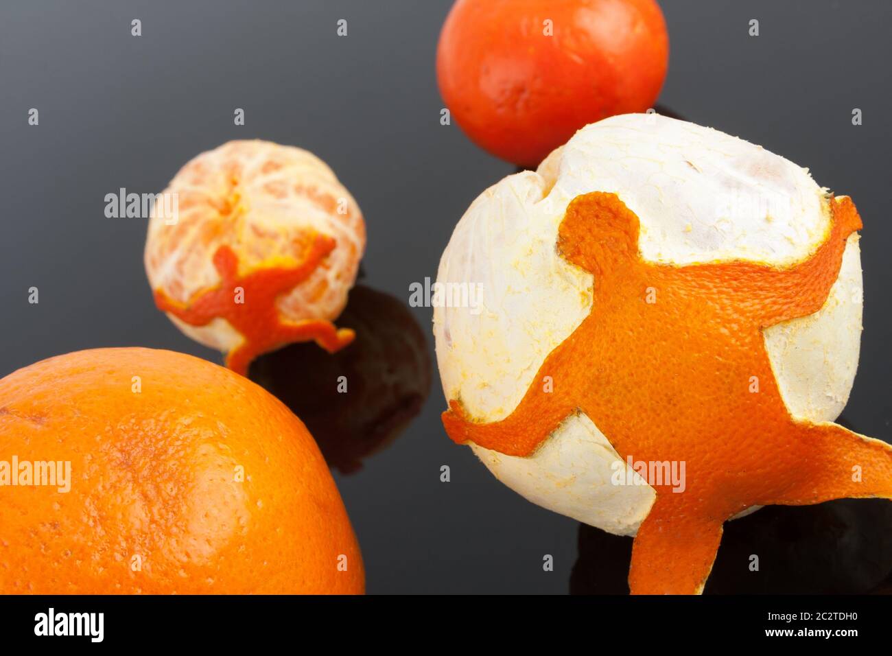 Figures of men of tangerine skin pushing a big tangerines over grey ...