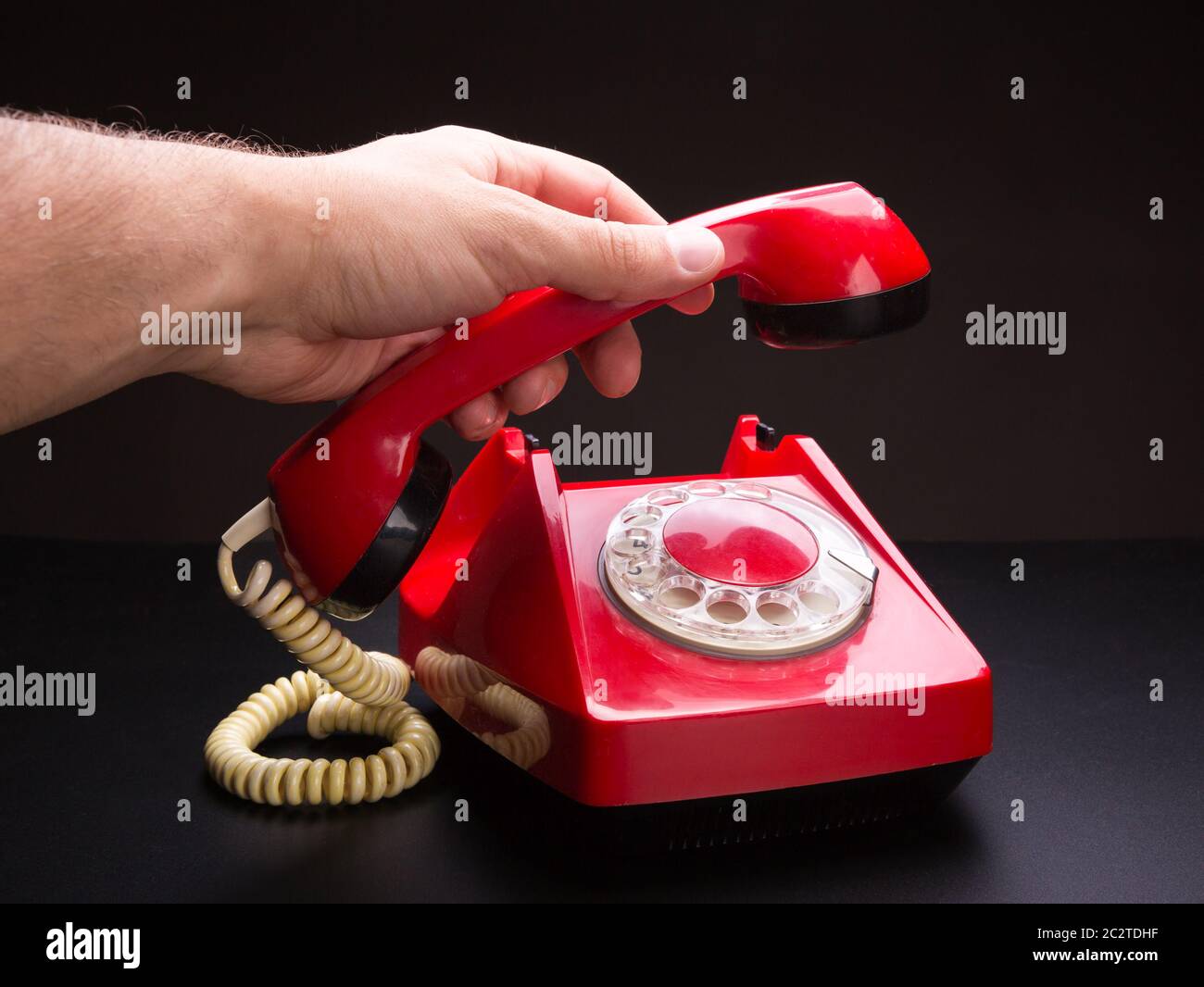 Hand picking up handset of red telephone Stock Photo - Alamy