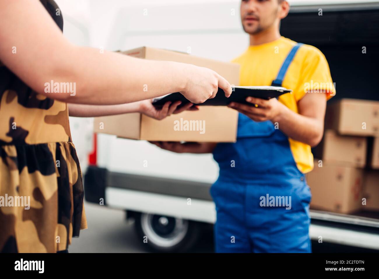 Cargo delivery service, male courier in uniform gives a parcel to the ...