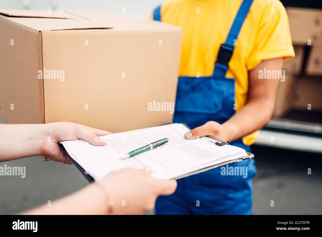 Male worker in uniform gives a parcel to the client, distribution ...