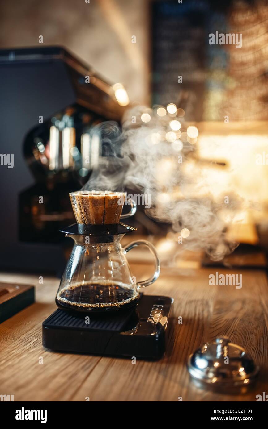 Glass coffee pot with steam on wooden counter, espresso machine on ...