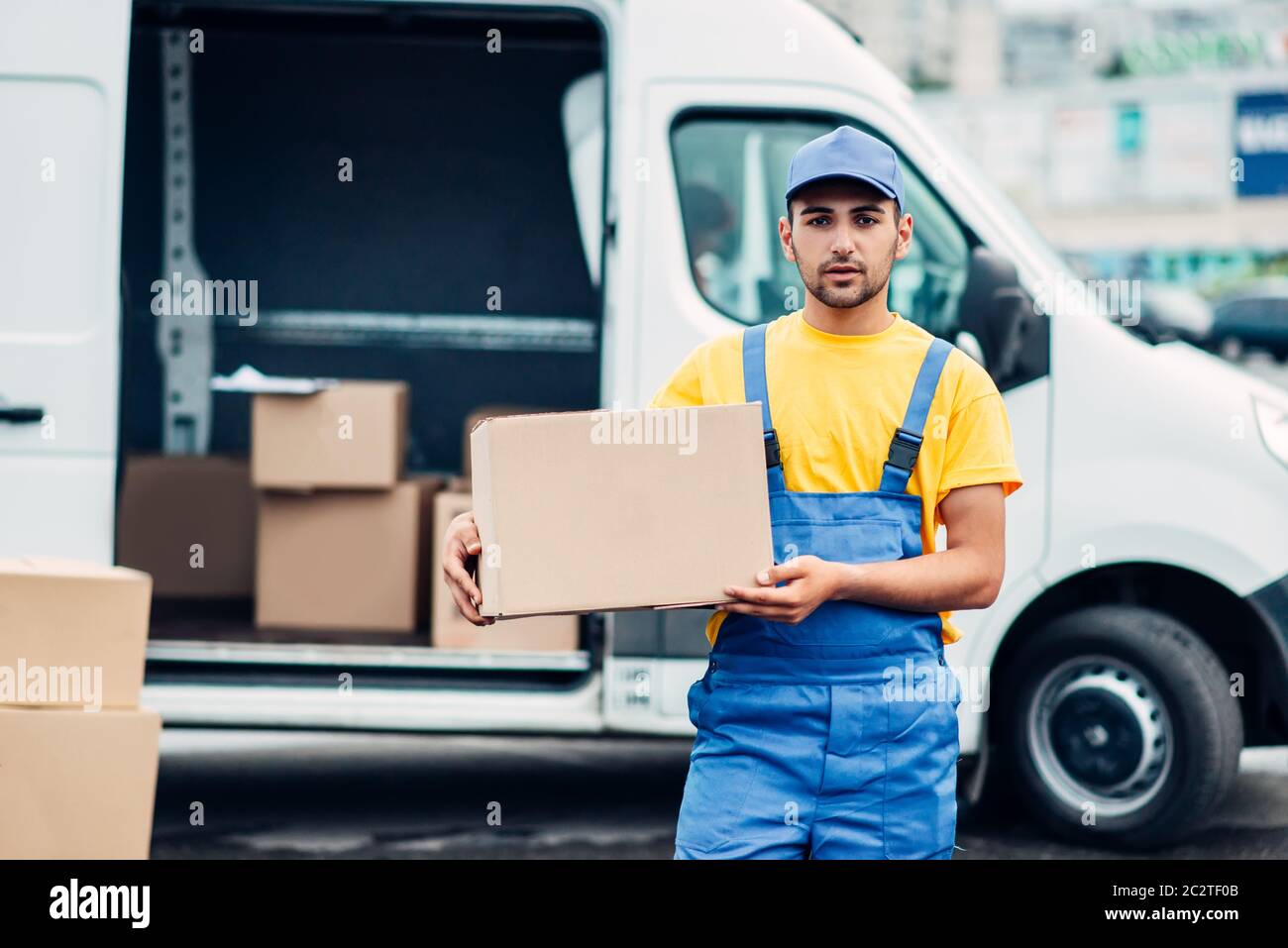 Cargo delivery service, male courier in uniform with box in hand ...