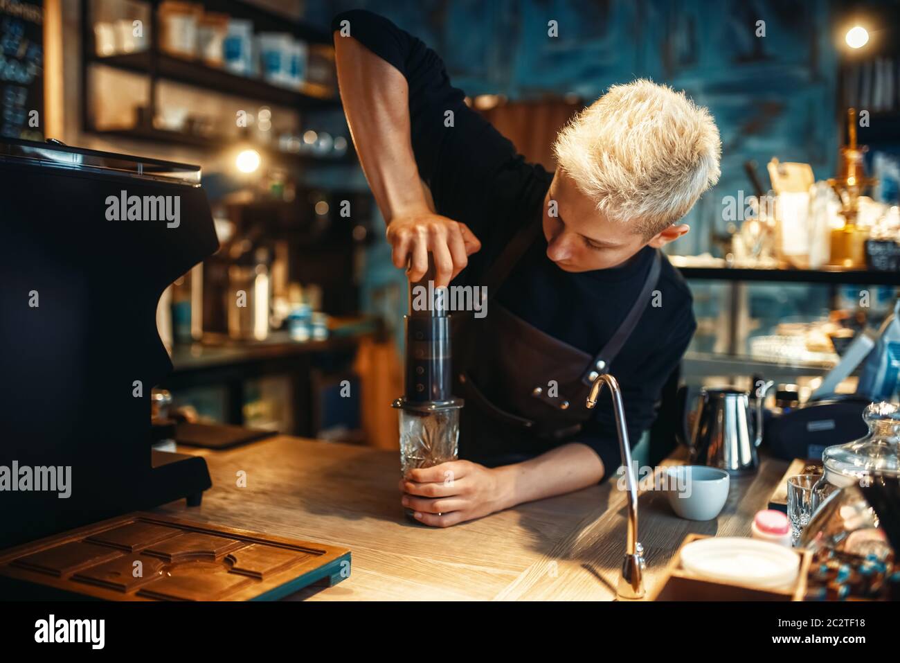 Young male barista makes fresh espresso, black coffee preparation at ...