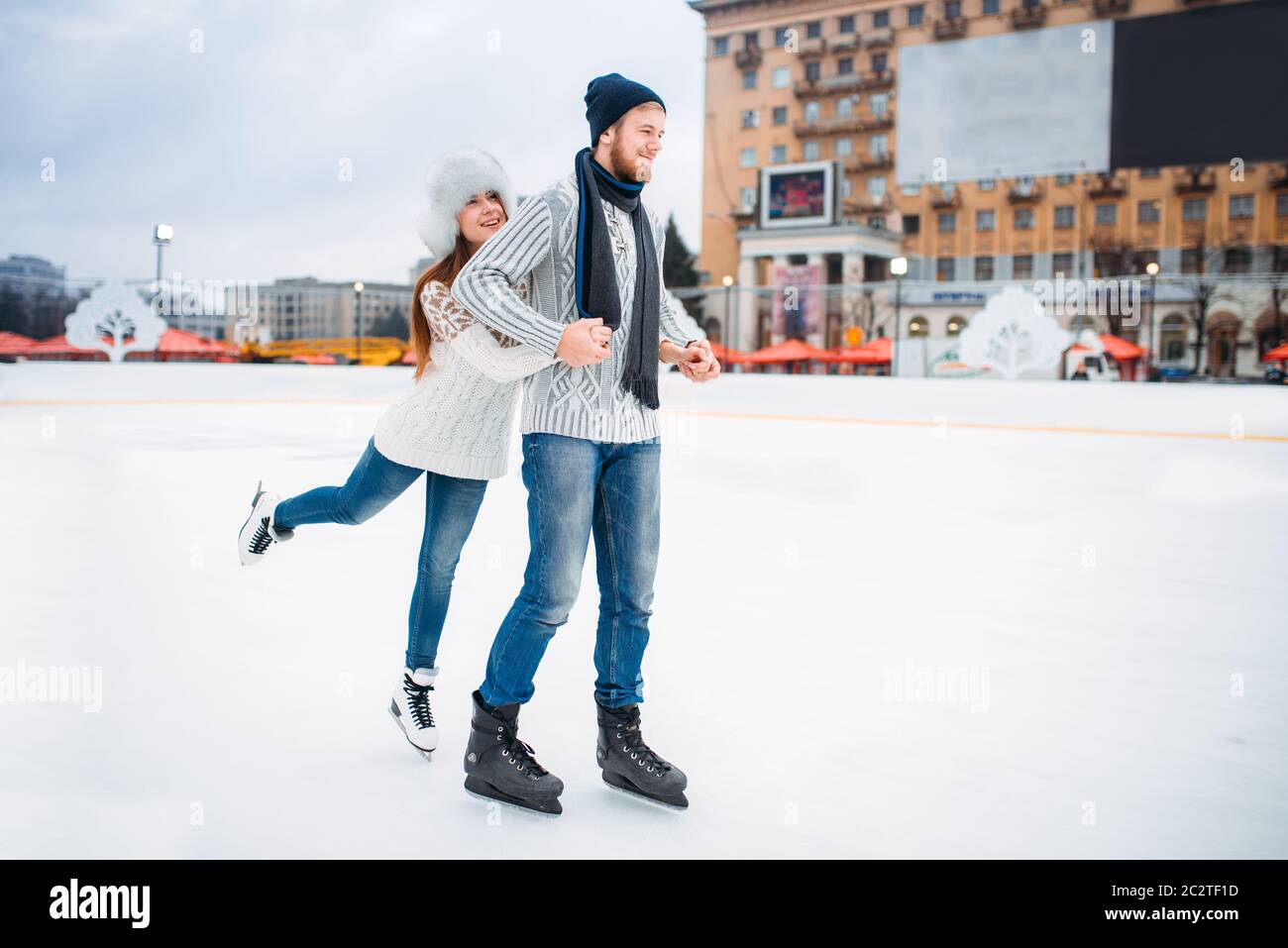 Happy love couple poses on skating rink. Winter ice-skating on open air ...