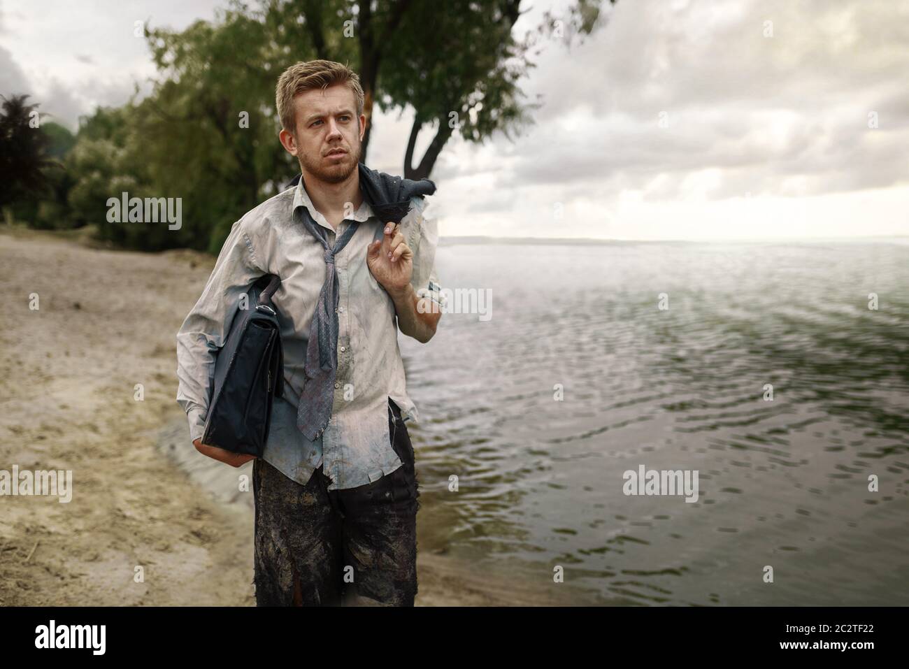 Alone businessman in torn suit walking on the beach on desert island ...