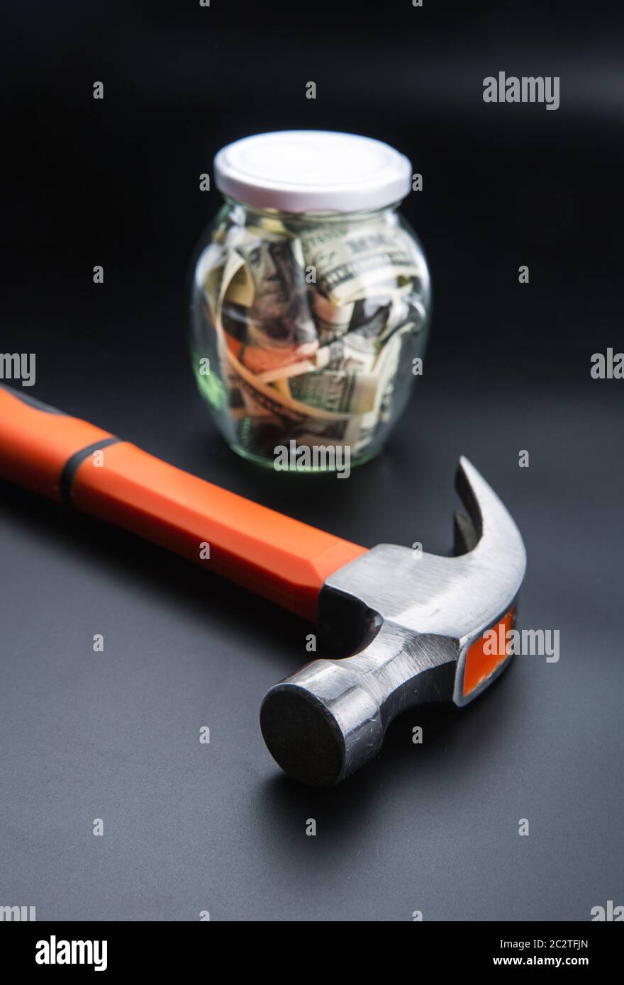 Money saving control concept, hammer against glass jar full of dollars ...