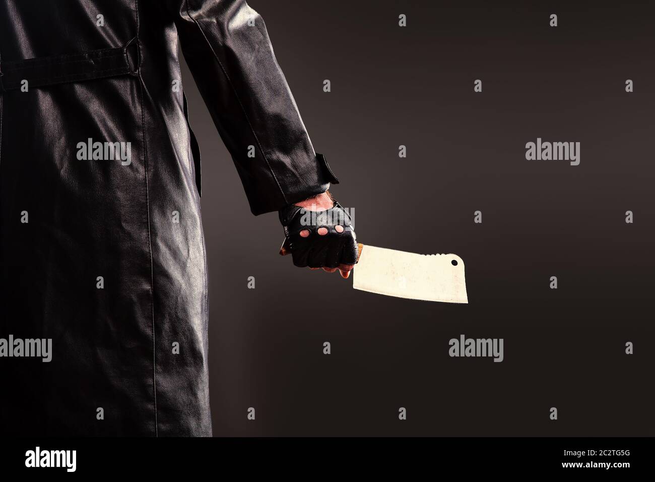 Killer in black leather coat holding meat cleaver in hand against black ...